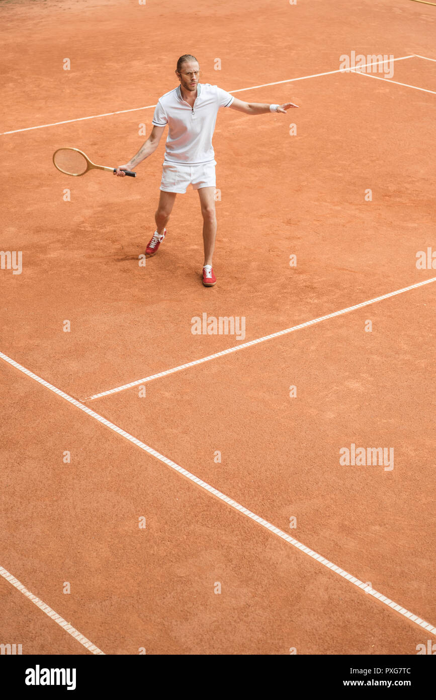 old-fashioned tennis player training with retro wooden racket on brown ...