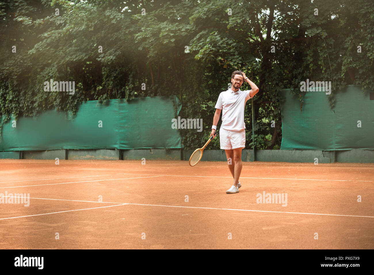 handsome tennis player with racket standing on tennis court Stock Photo ...