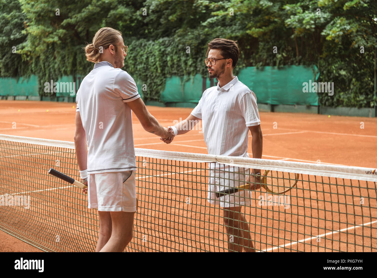 athletic tennis players with wooden rackets shaking hands after match ...