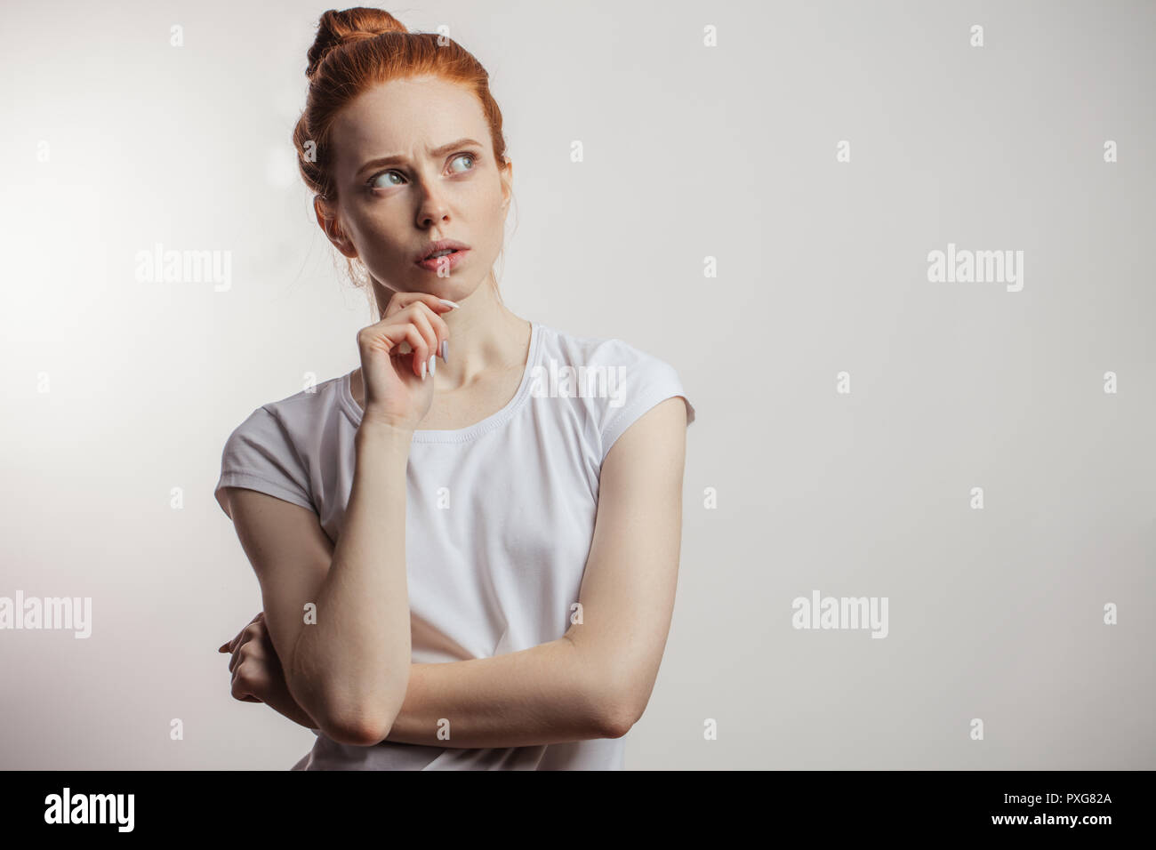 Redhaired woman looking up with pensive expression isolated on white ...