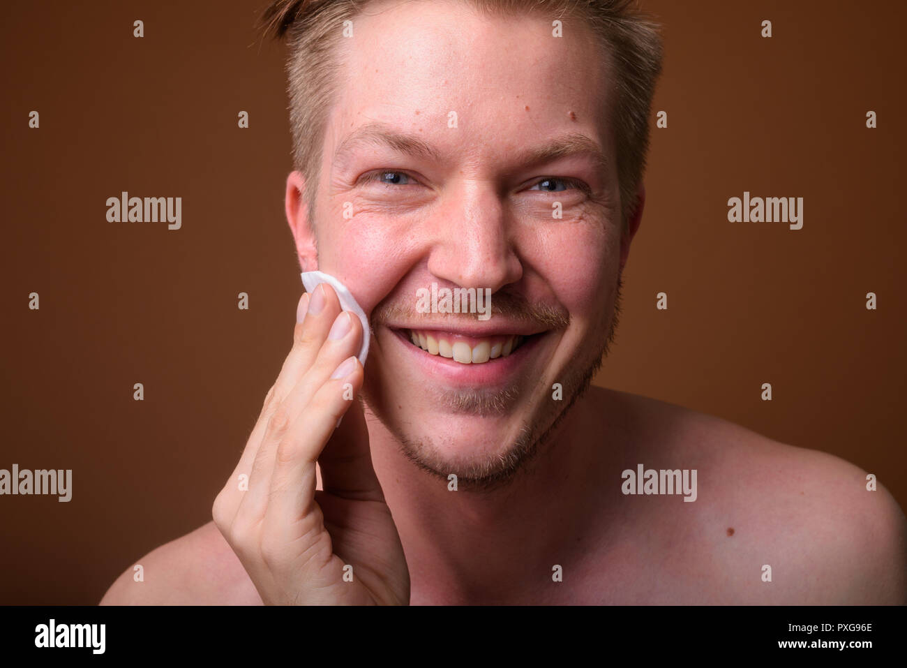 Young handsome man shirtless while grooming against brown backgr Stock Photo - Alamy