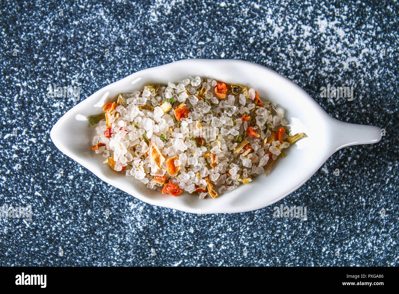 Different types of salt in glass bowls on a dark gray table. Background ...