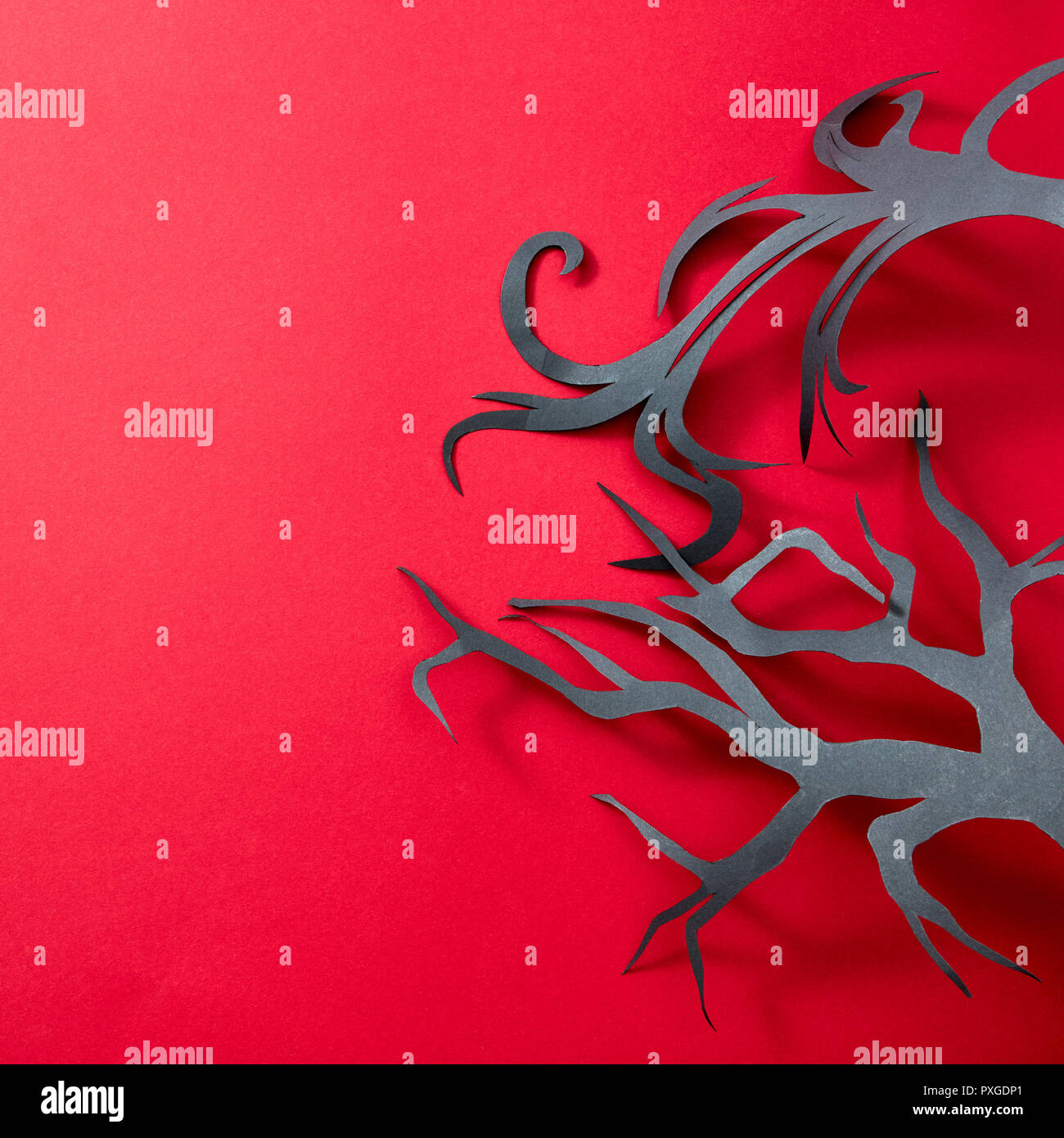 Handcraft black tree from paper on a red background with reflection of ...