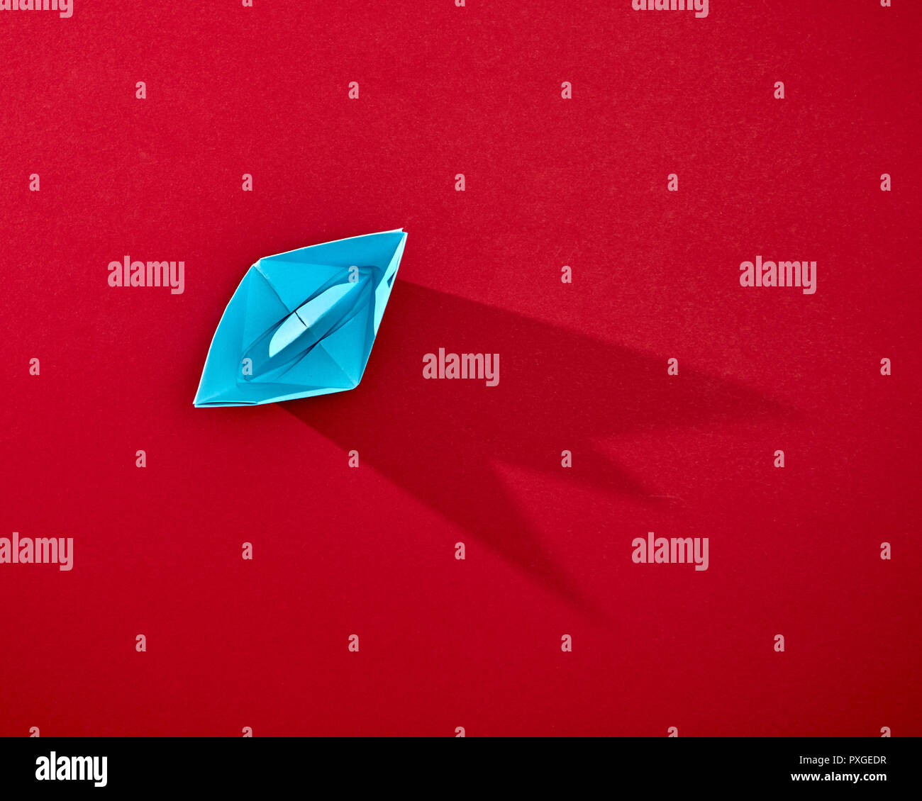Handcraft paper blue ship isolated on red background with reflection of ...
