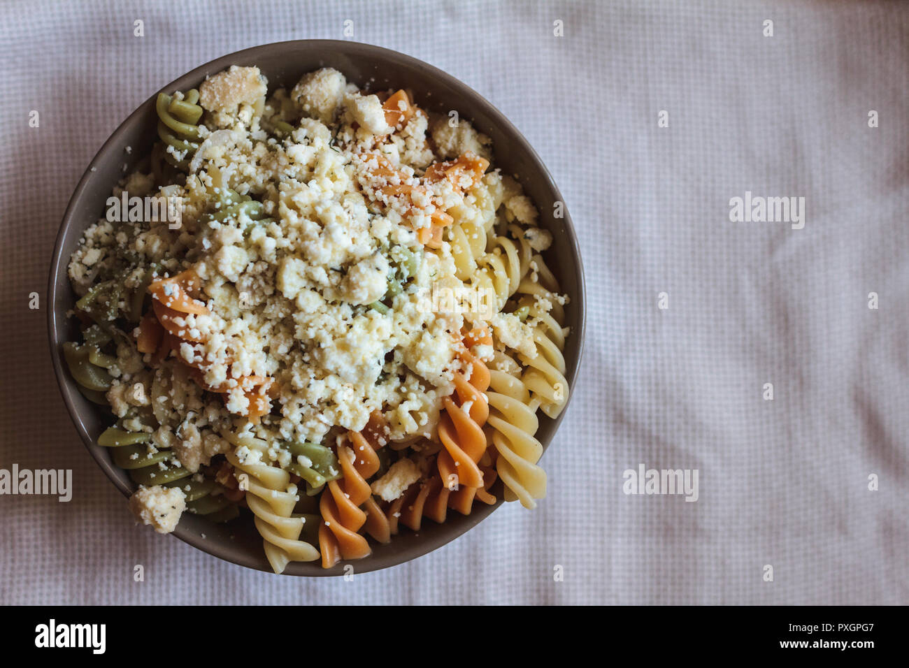 Tri color fusilli with cheese with dill in a grey bowl Stock Photo - Alamy