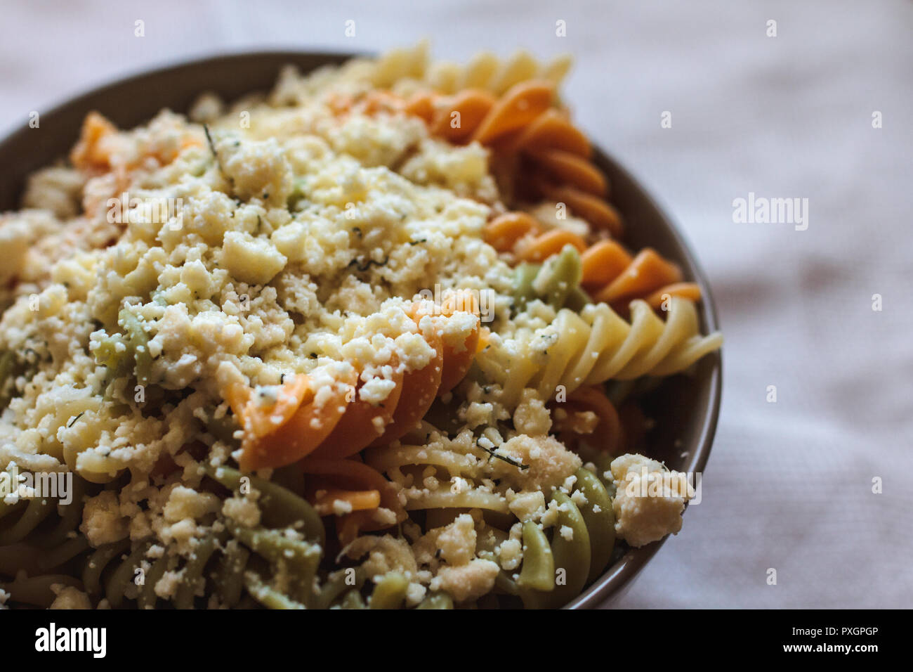 Tri color fusilli with cheese with dill in a grey bowl Stock Photo - Alamy