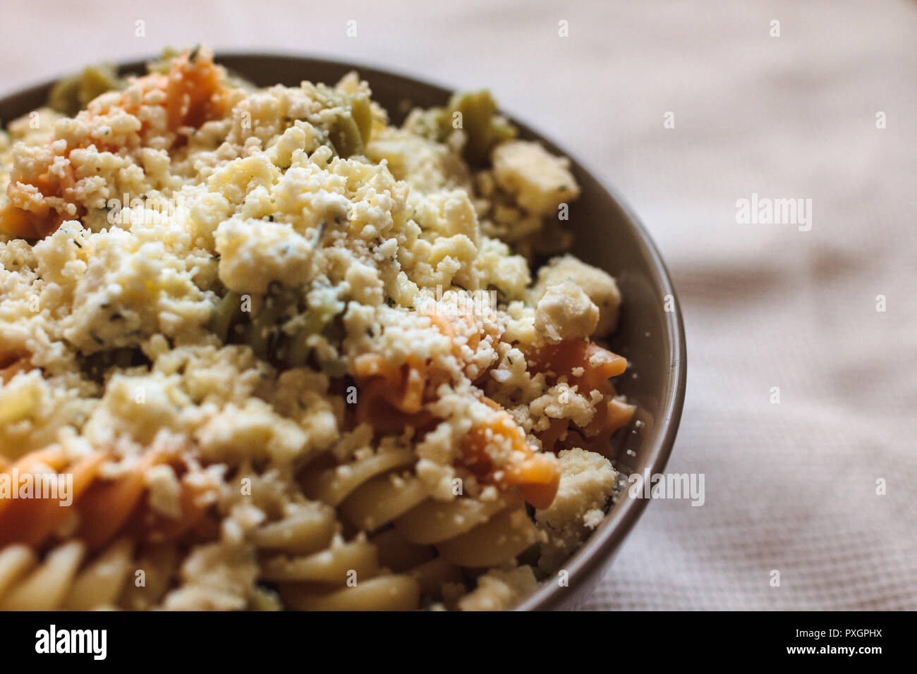 Tri color fusilli with cheese with dill in a grey bowl Stock Photo - Alamy