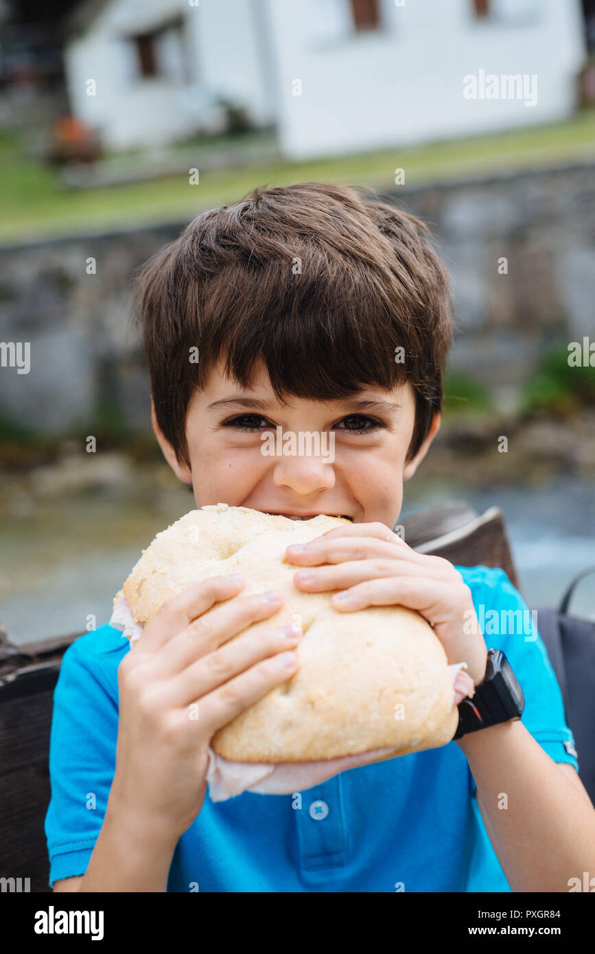 child eats a ham-stuffed sandwich during a mountain hike Stock Photo ...