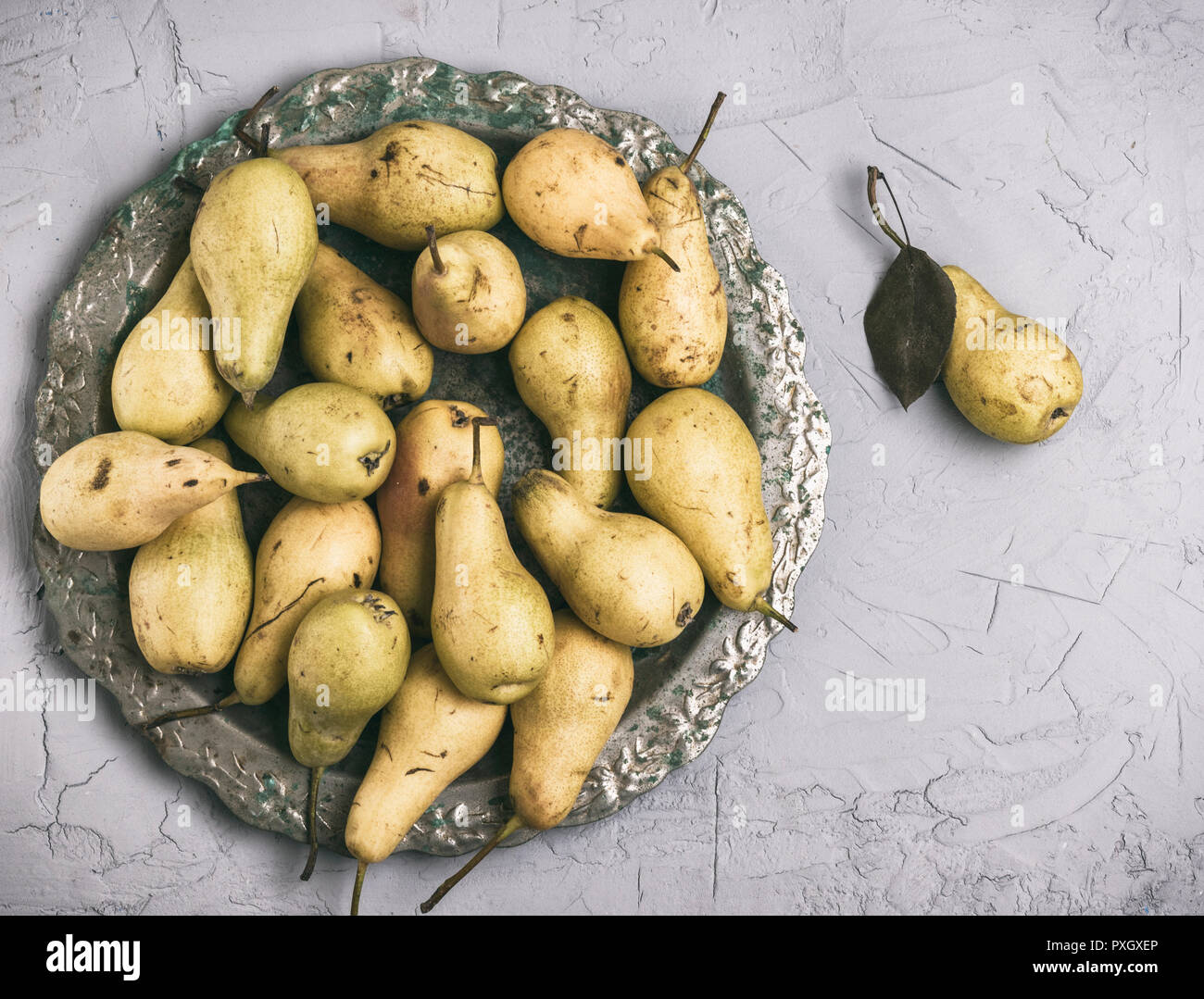 ripe yellow pears in an iron round plate, gray background, empty space ...