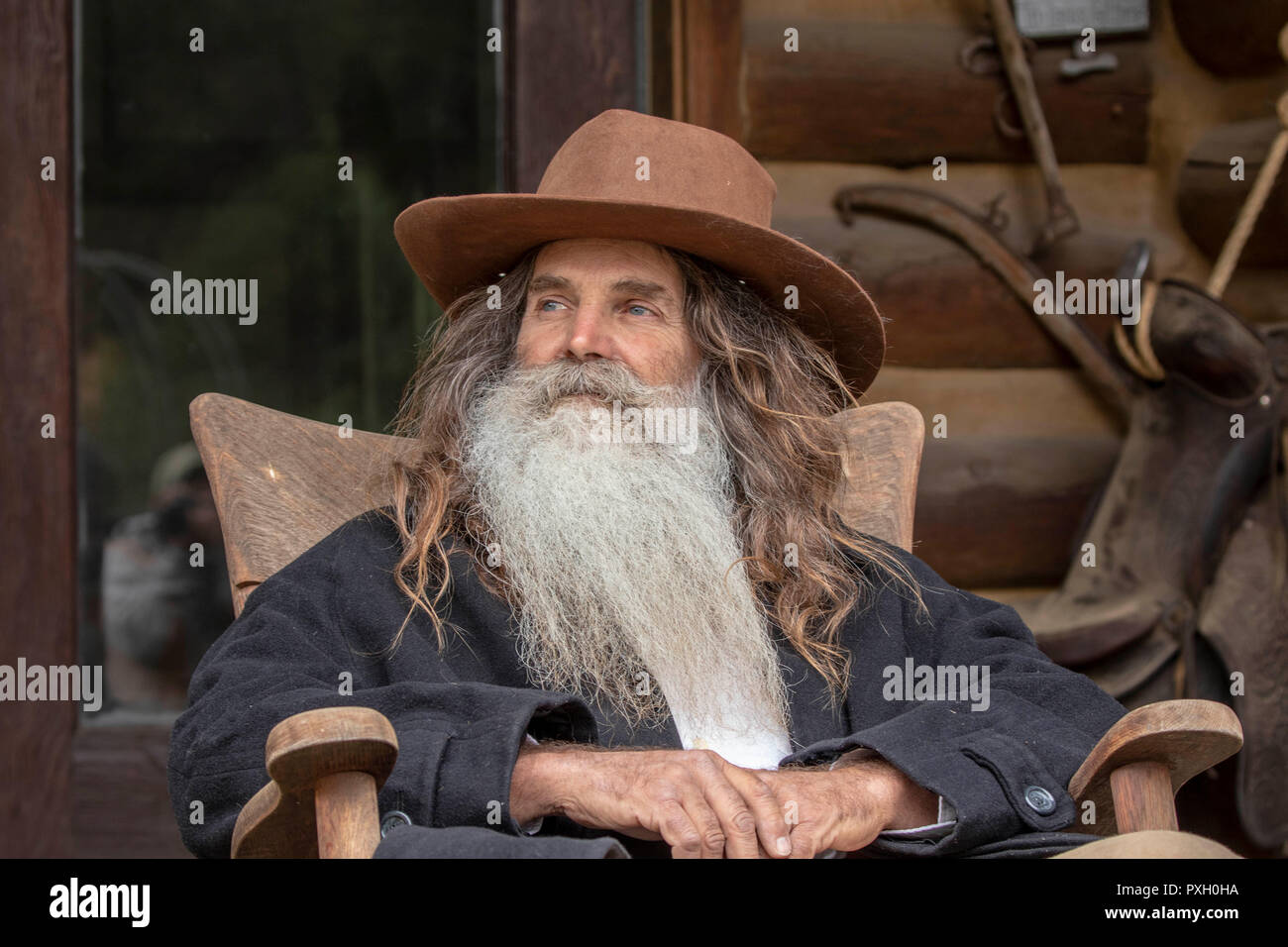 Western man in traditional clothing with a colt 45 sitting on a log ...