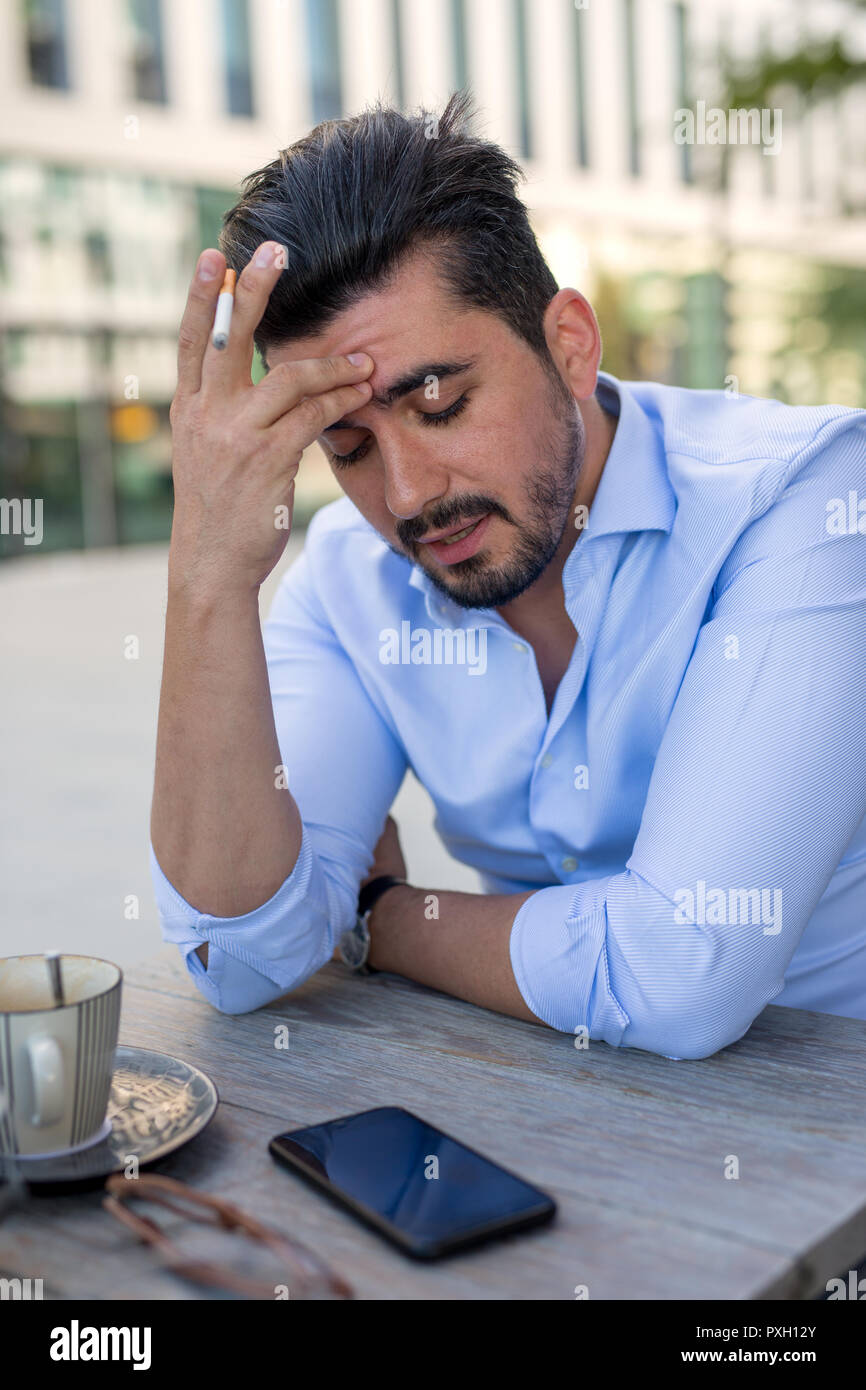 Stressed out businessman with a cigarette holding his head Stock Photo ...