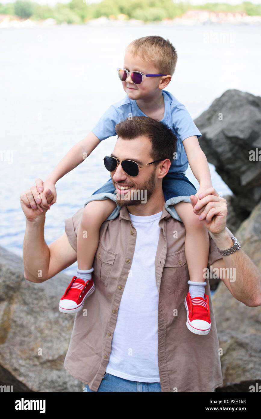 happy dad holding son on shoulders and they looking away at park Stock ...