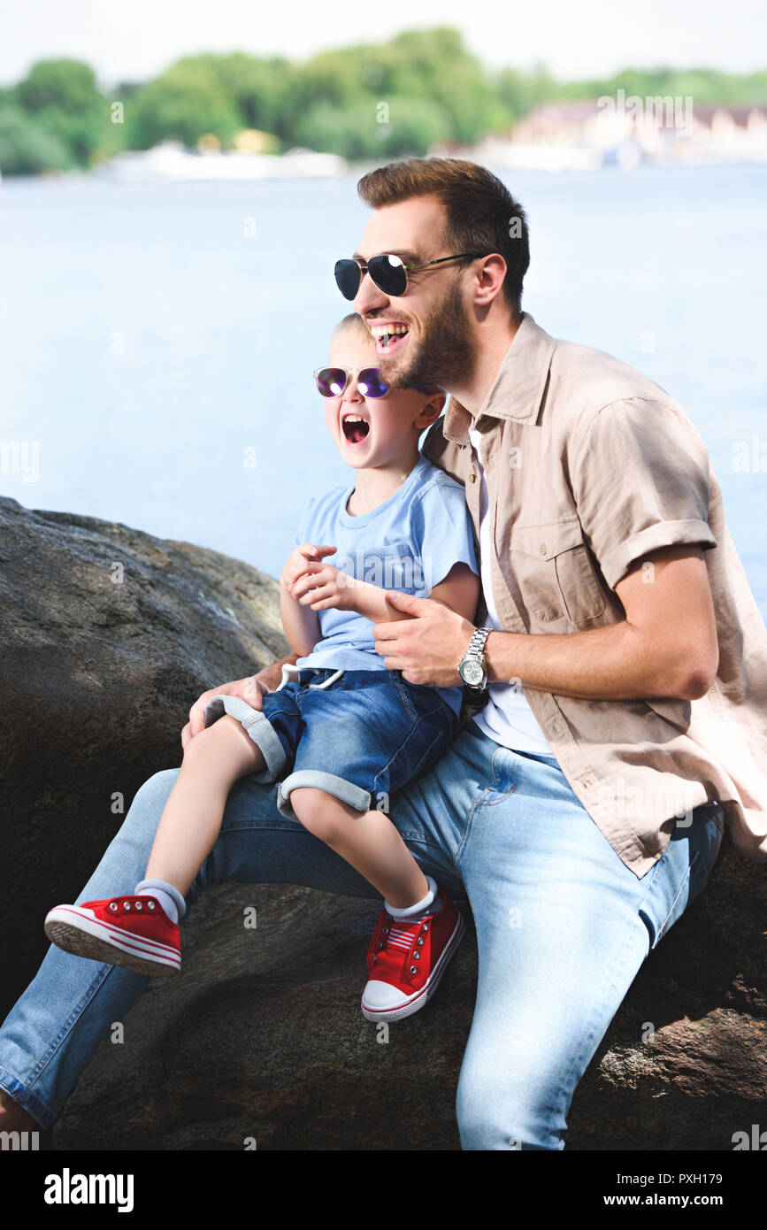 laughing father and son looking away at park Stock Photo - Alamy