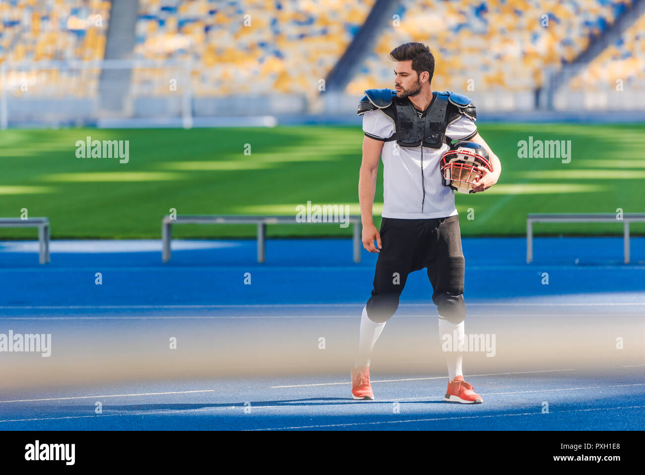 athletic american football player standing alone at sports stadium ...