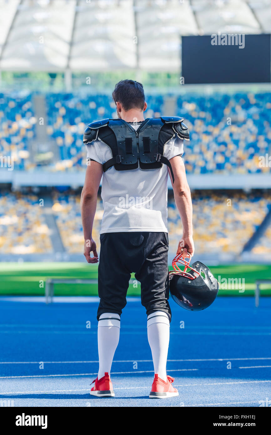rear view of american football player with helmet standing alone at ...