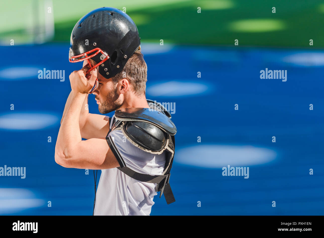 young american football player putting on helmet at sports stadium ...