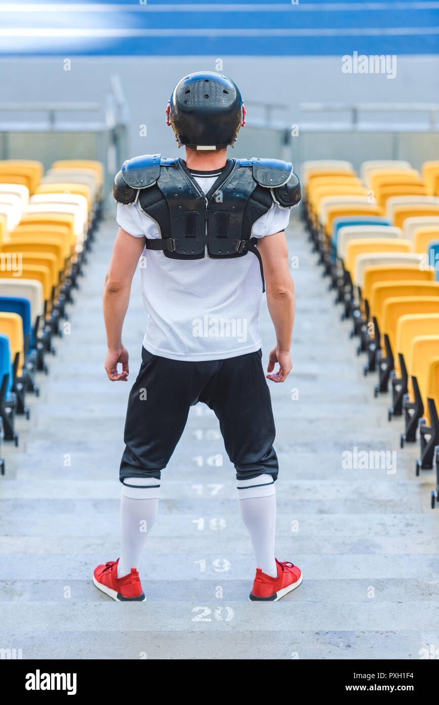 rear view of athletic american football player on stairs at sports ...