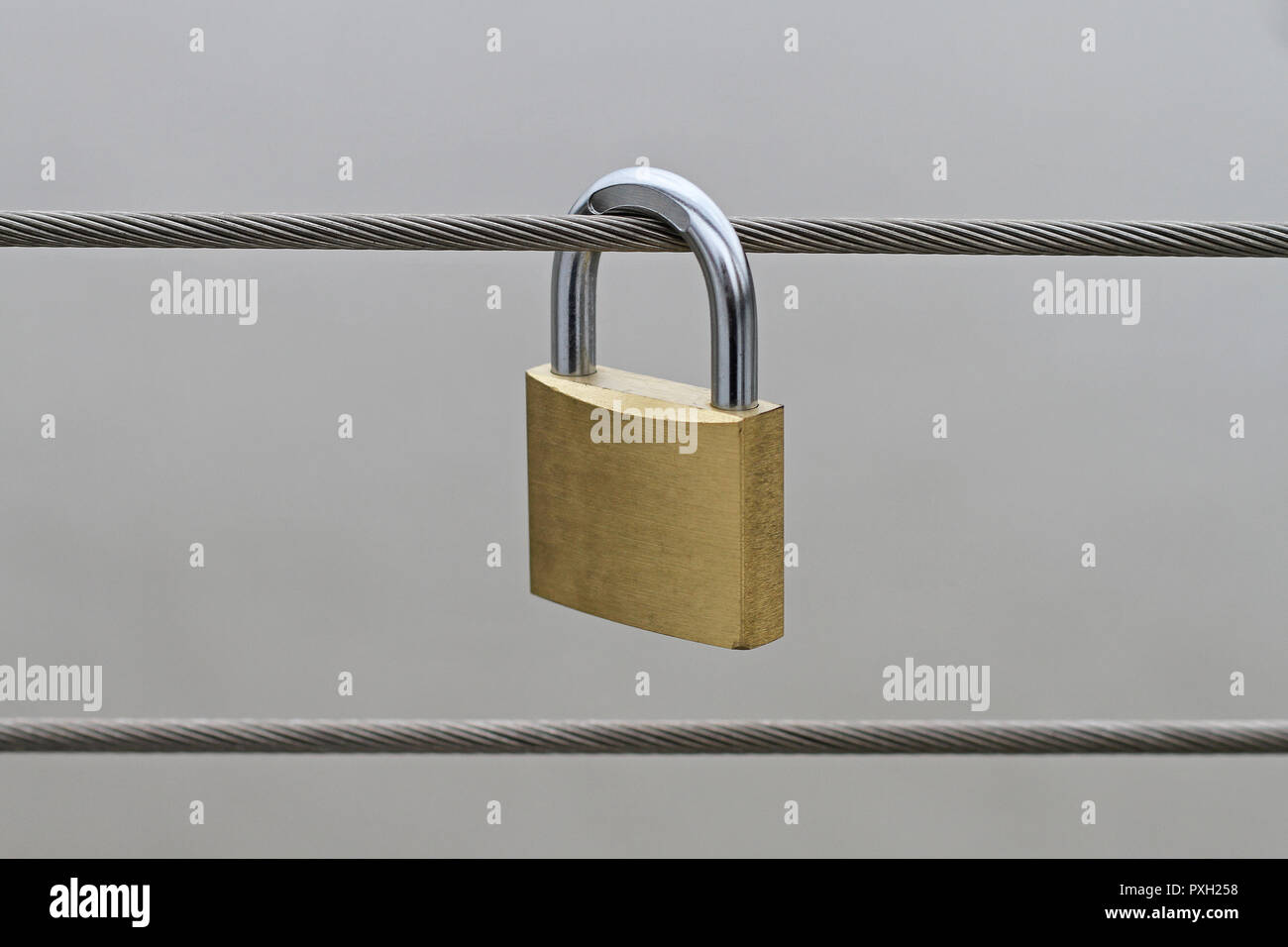 Locked brass safety padlock at metal cable Stock Photo - Alamy
