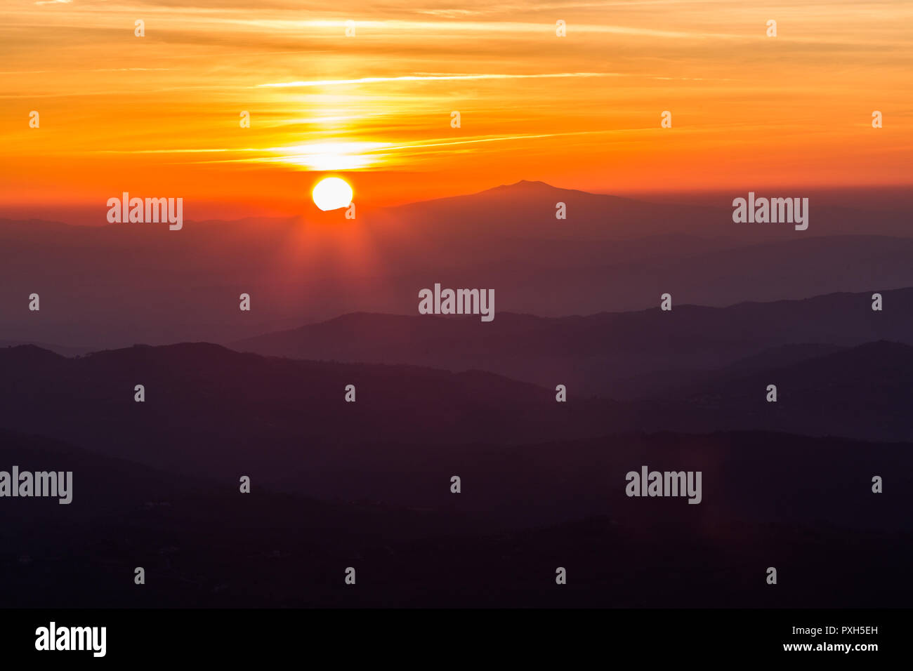 Beautiful sunset with sun coming down behind various layers of ...