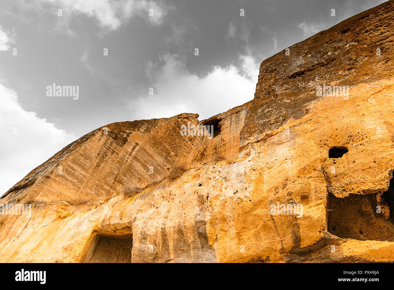 Golden cliff shot from the bottom up, gray cloudy sky, rock texture ...