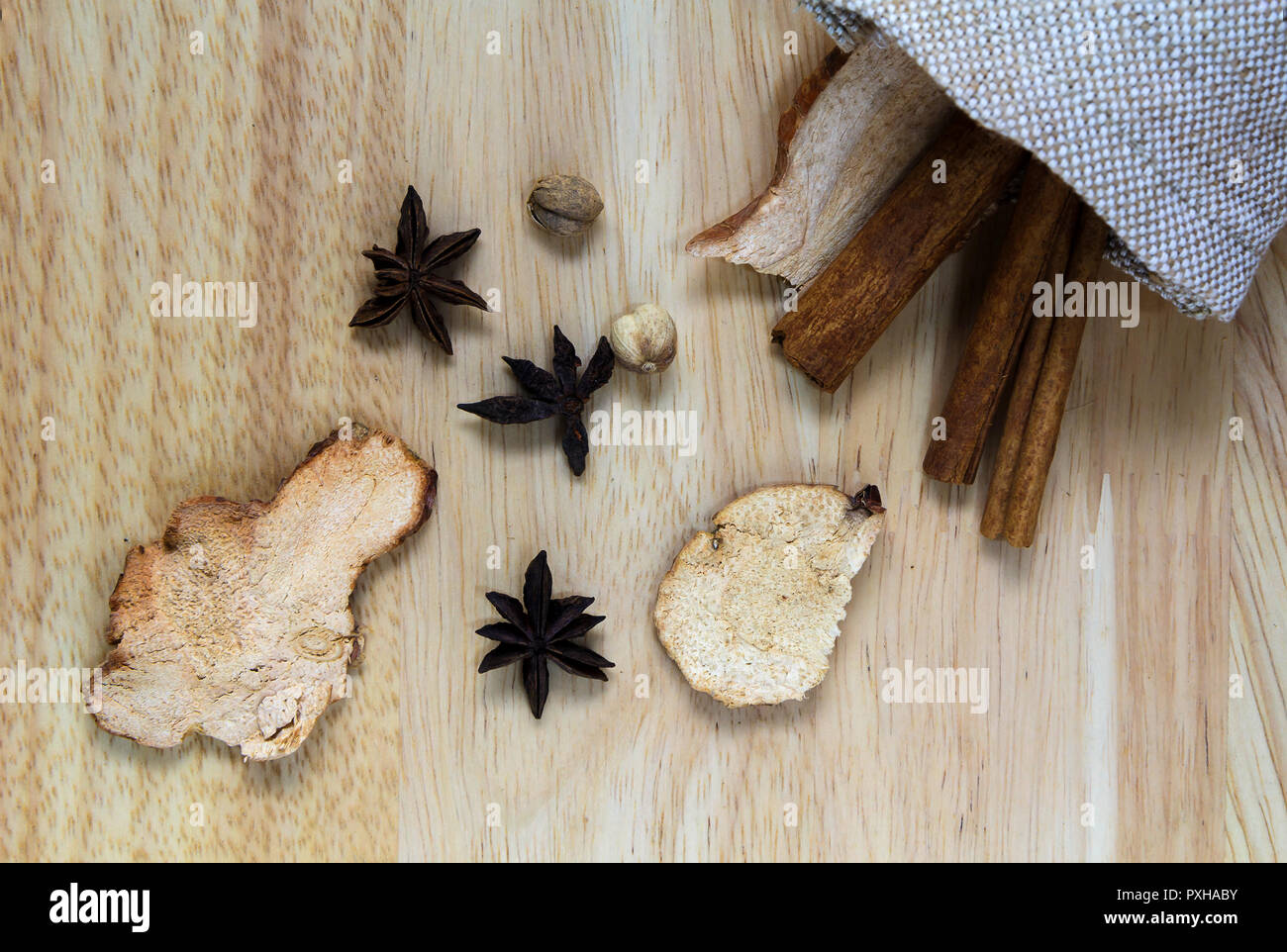 Cinnamon stick with spices and dried ginger in sack on wooden desk ...
