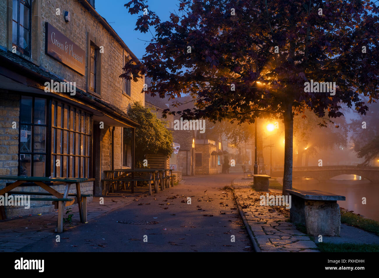 Mist and fog at dawn in the cotswold village of Bourton on the Water in ...