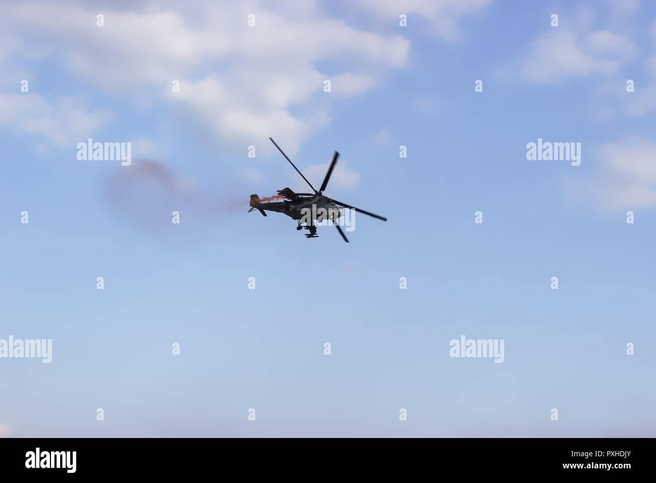 Combat helicopter on blue sky with white clouds. View from the bottom ...