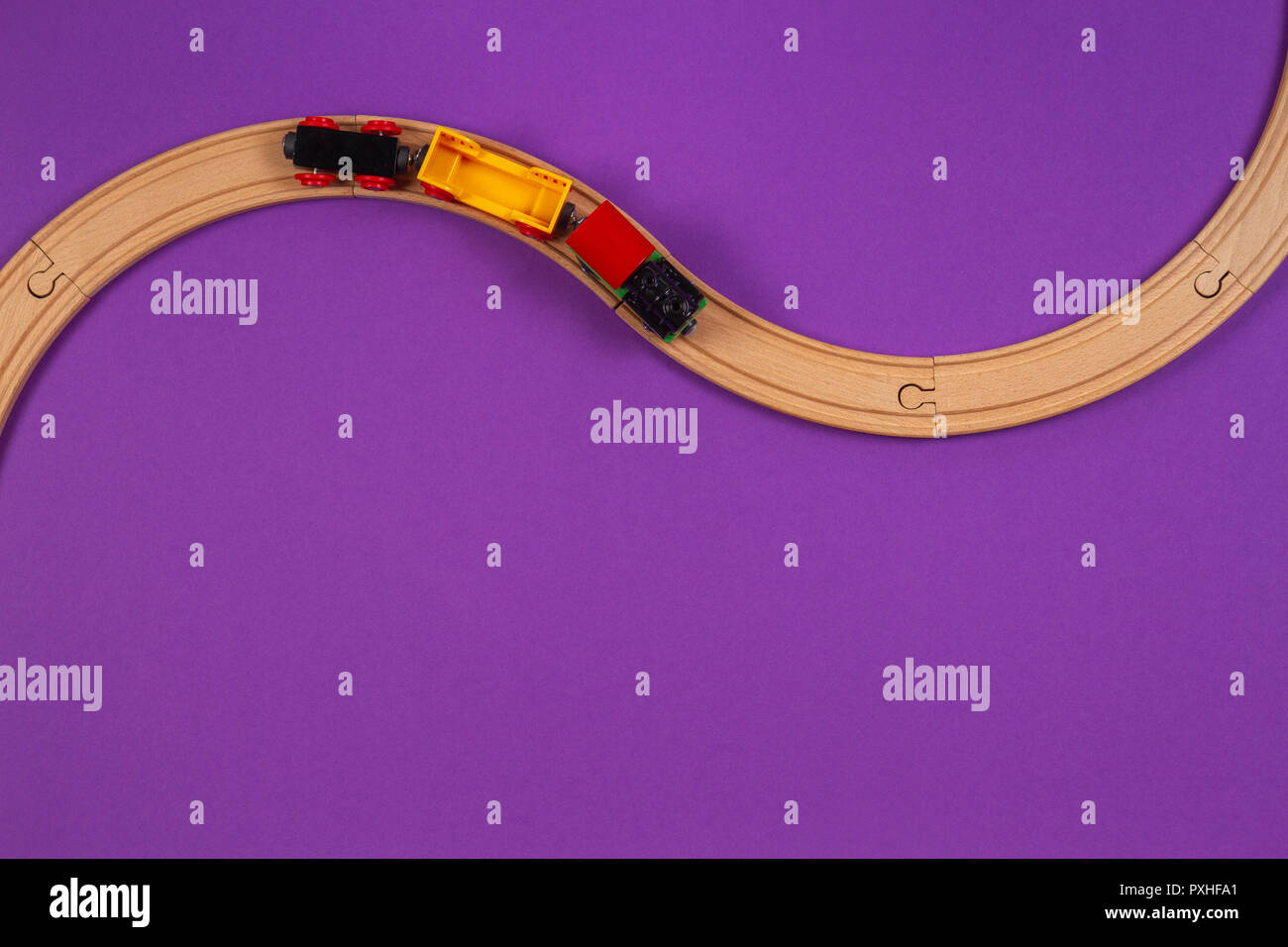 Toy train and wooden rails on purple violet background Stock Photo - Alamy