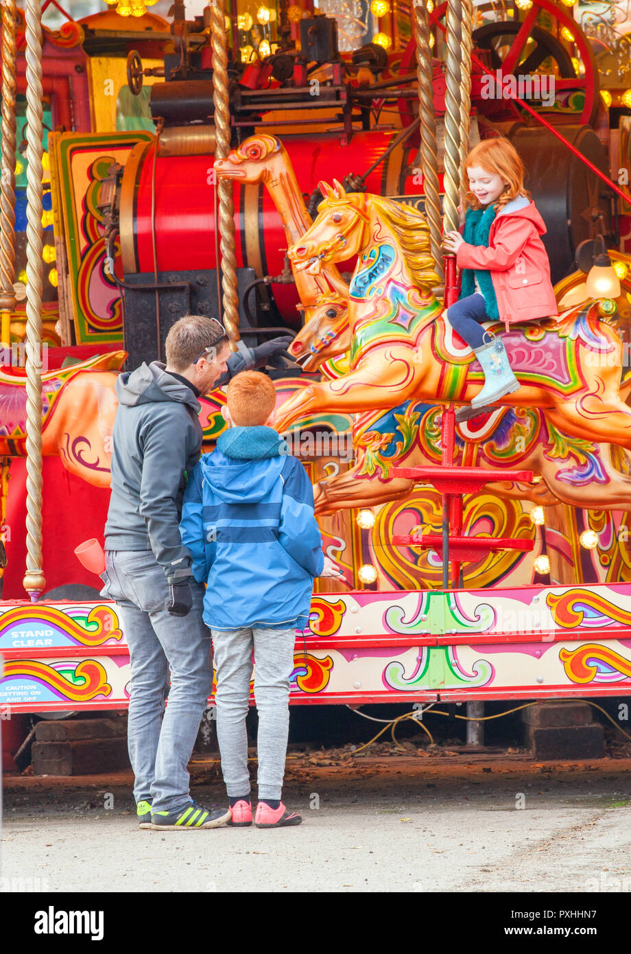 Family mother and father watching child on the hobby horse on the ...