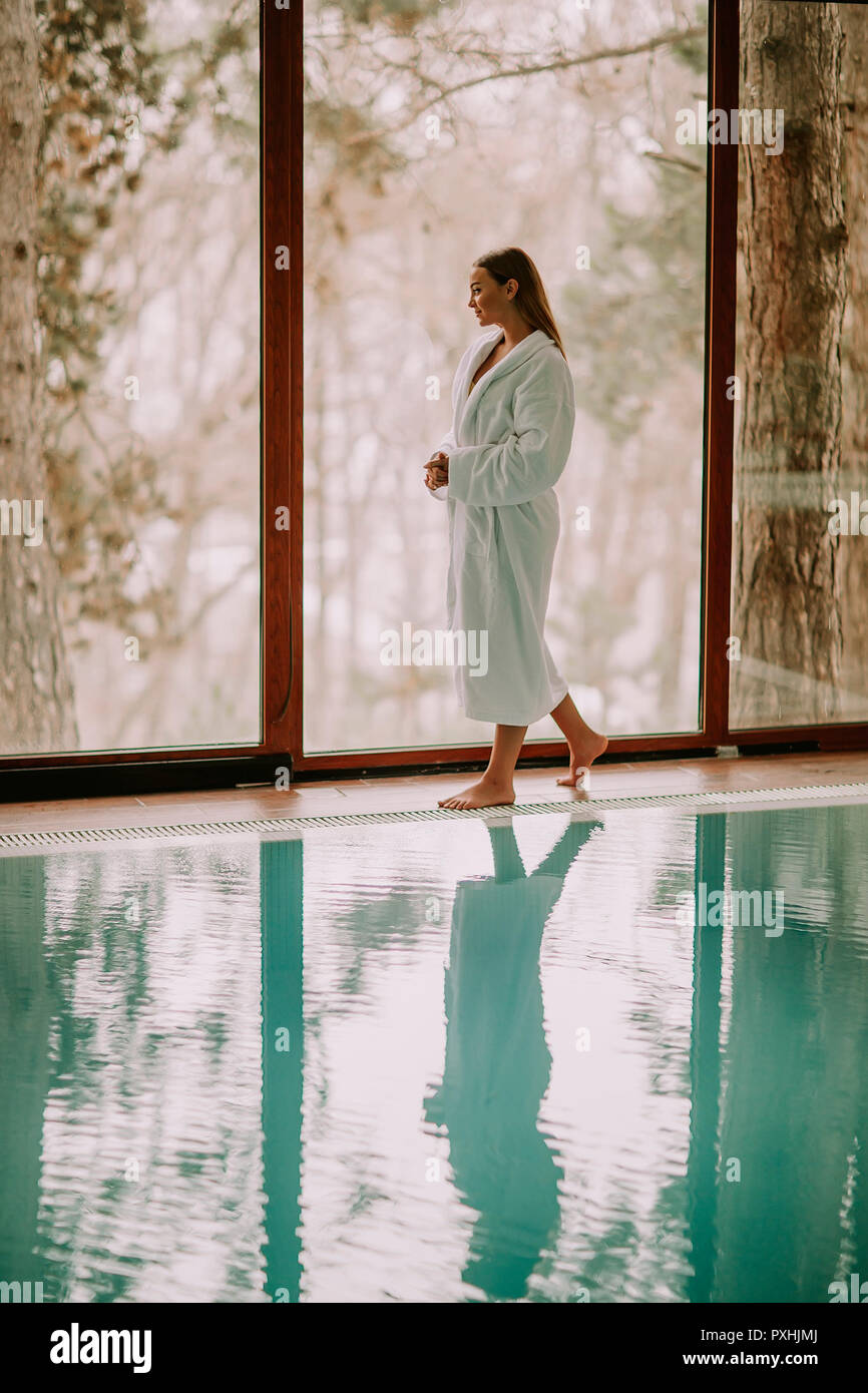 Pretty young woman in bathrobe standing by swimming pool Stock Photo ...
