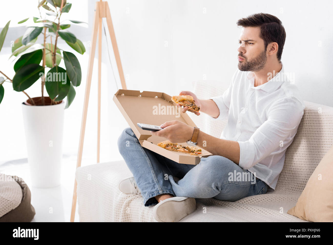 man eating pizza while watching tv alone at home Stock Photo - Alamy