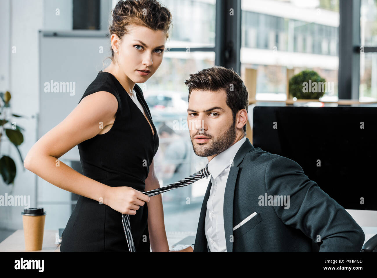 side view of businesswoman holding colleagues tie while flirting at ...