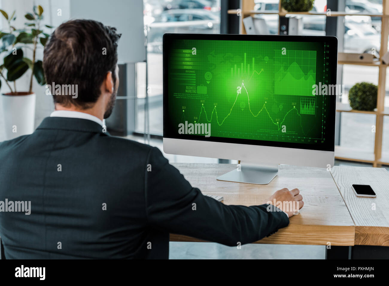 back view of businessman at workplace with computer screen with diagram ...
