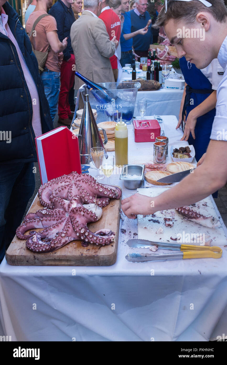 Large cooked octopus on wooden board being cut up for customers at the ...