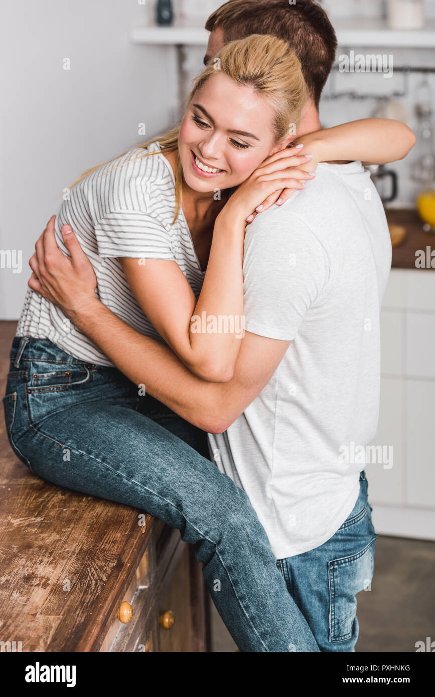 happy girlfriend sitting on kitchen counter and hugging boyfriend Stock ...