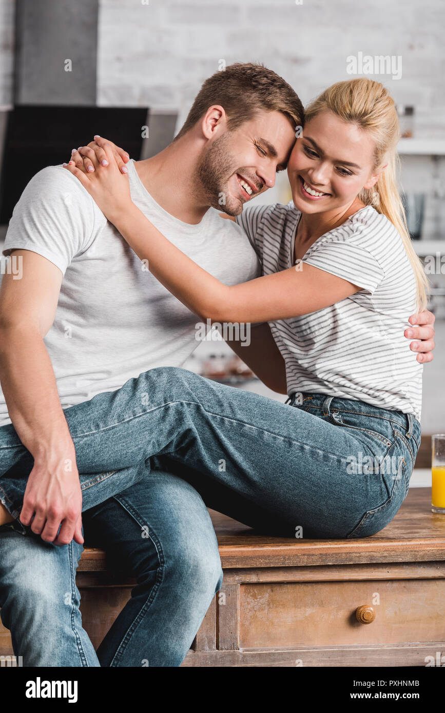 happy couple cuddling and sitting on kitchen counter Stock Photo - Alamy