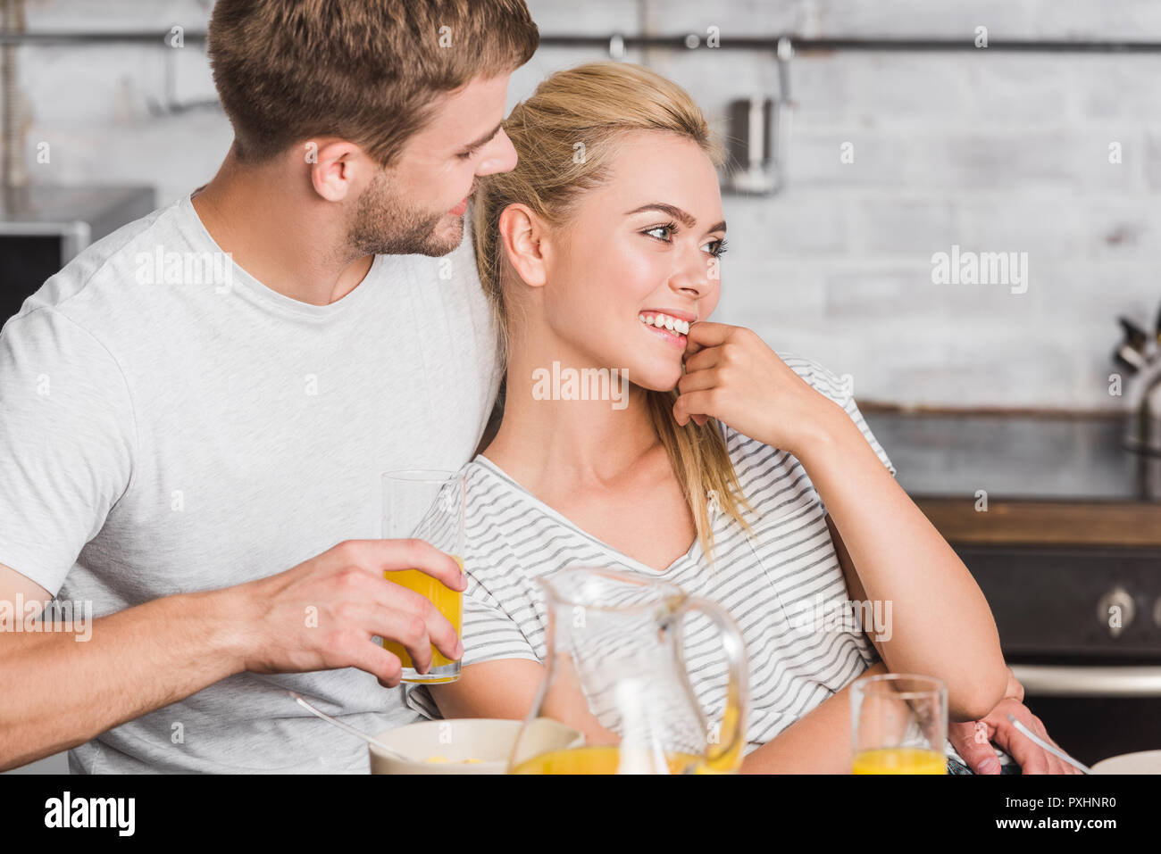 happy boyfriend hugging girlfriend during breakfast in kitchen Stock ...