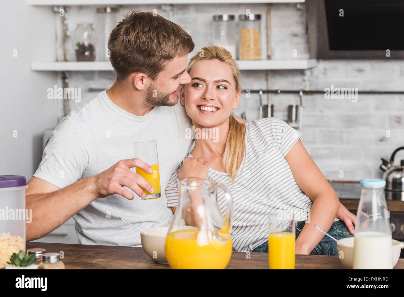 happy boyfriend hugging girlfriend during breakfast in kitchen and they ...
