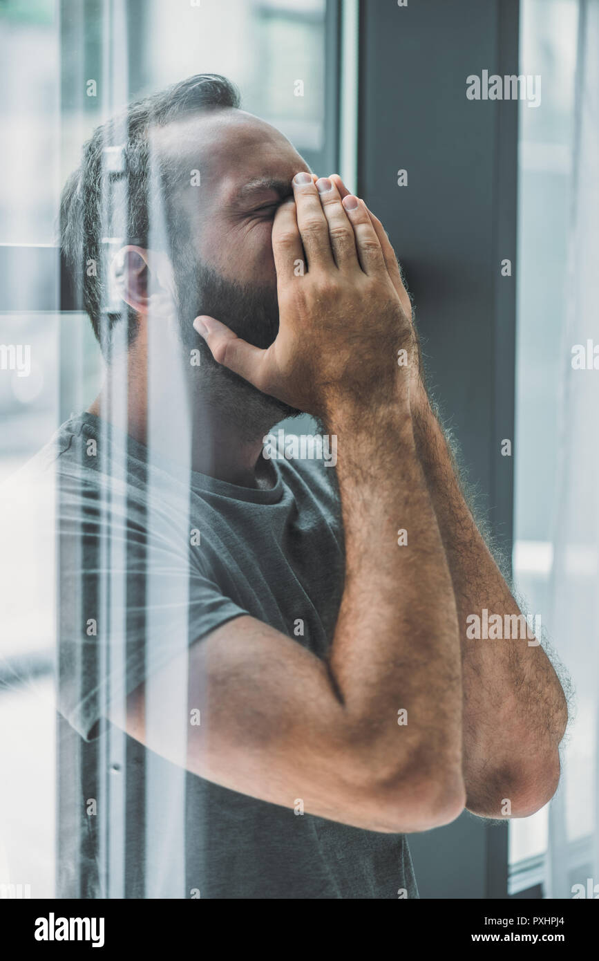 side view of depressed frustrated bearded man crying with hands on face ...