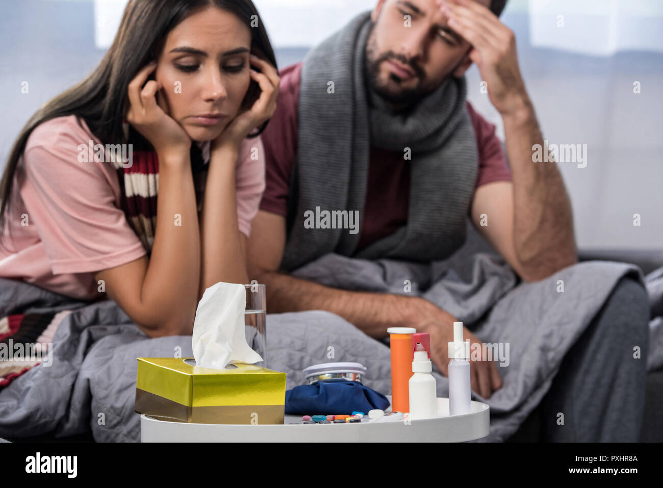 sick couple with meds on table sitting together on couch Stock Photo ...