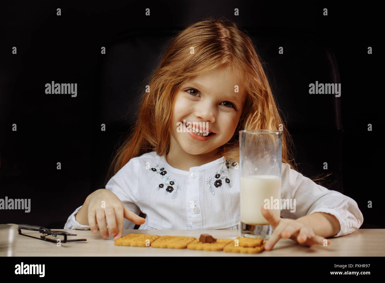 Happy beautiful little girl having a snack with milk and cookies Stock ...
