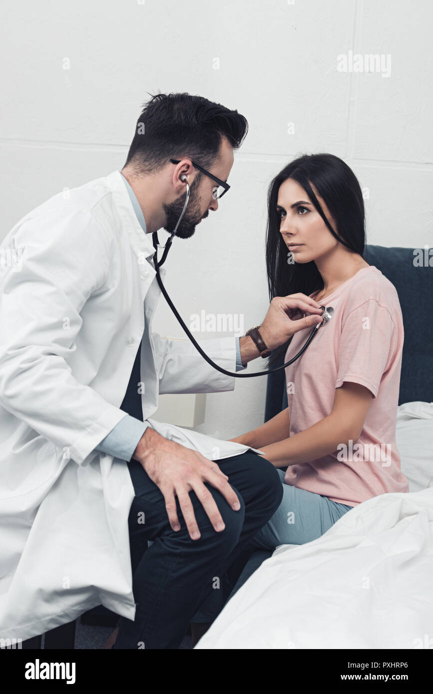 confident young doctor listening breath of female patient Stock Photo ...
