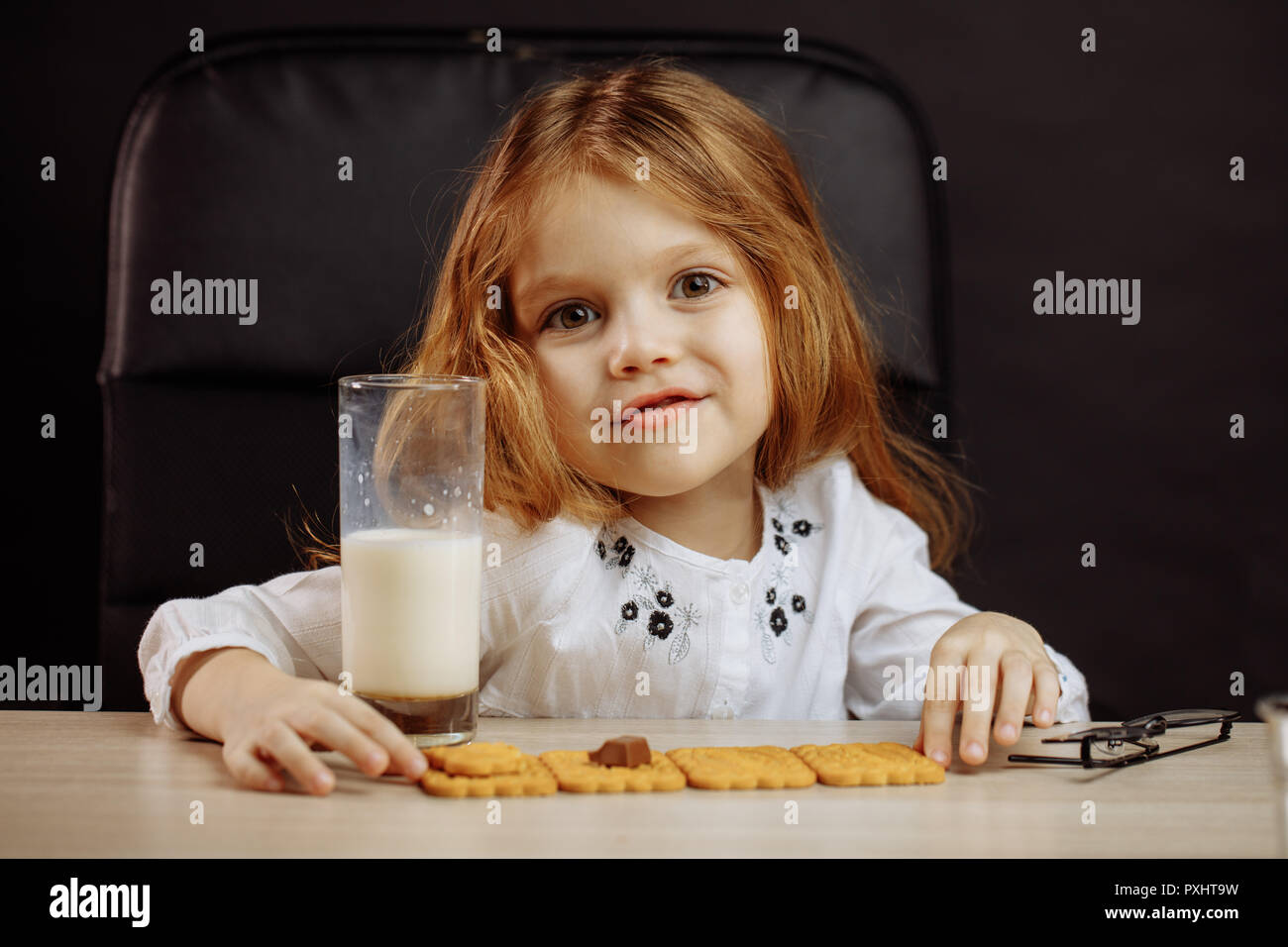 Happy beautiful little girl having a snack with milk and cookies Stock ...