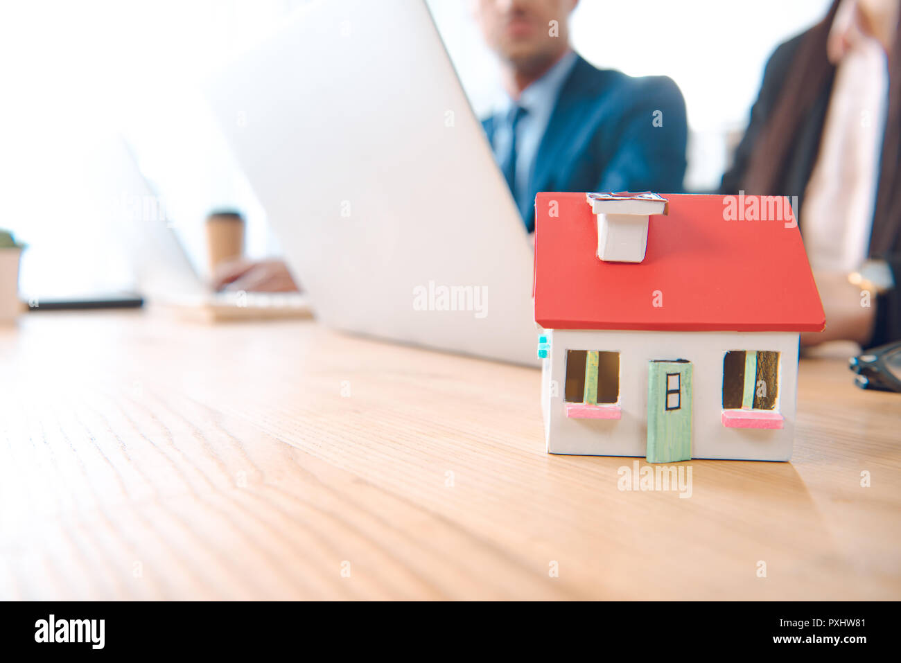 partial view of insurance agents at workplace with house model in ...