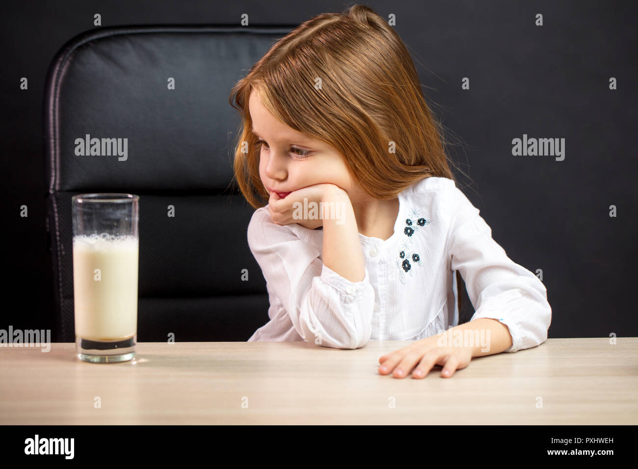 Gloomy little girl in glasses refusing to drink milk, over black Stock ...