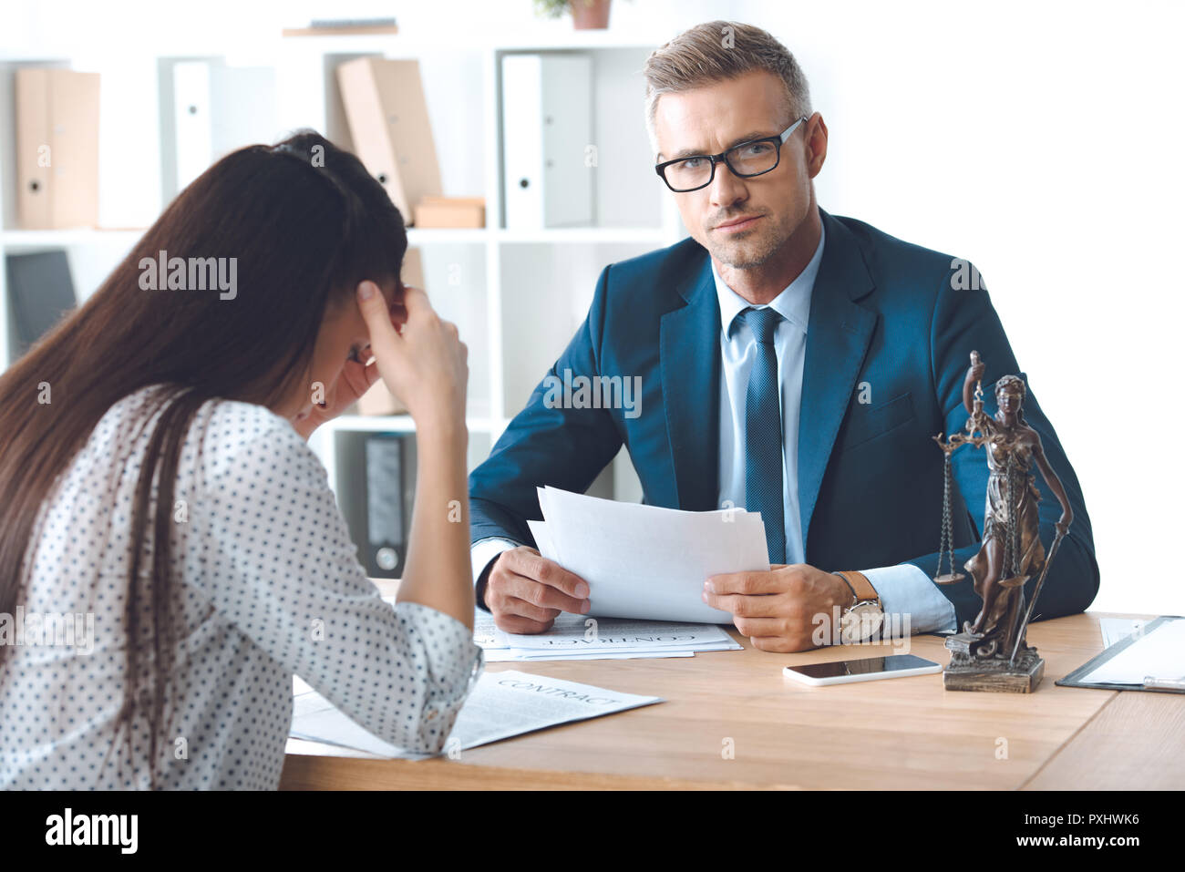 lawyer holding papers and looking at camera while working with sad ...