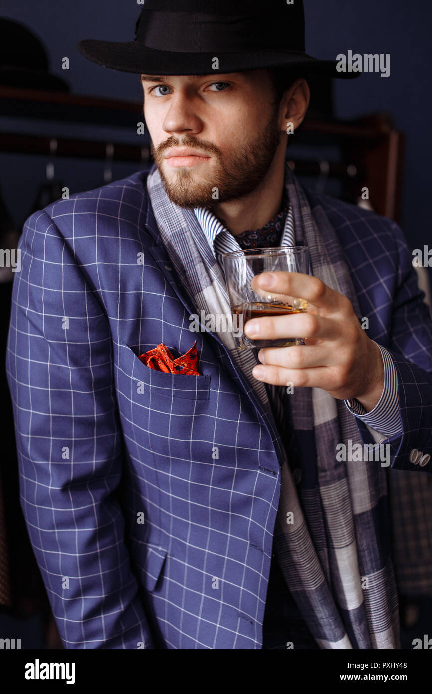 Elegant man in fashion suit and hat posing at atelier with beverage ...