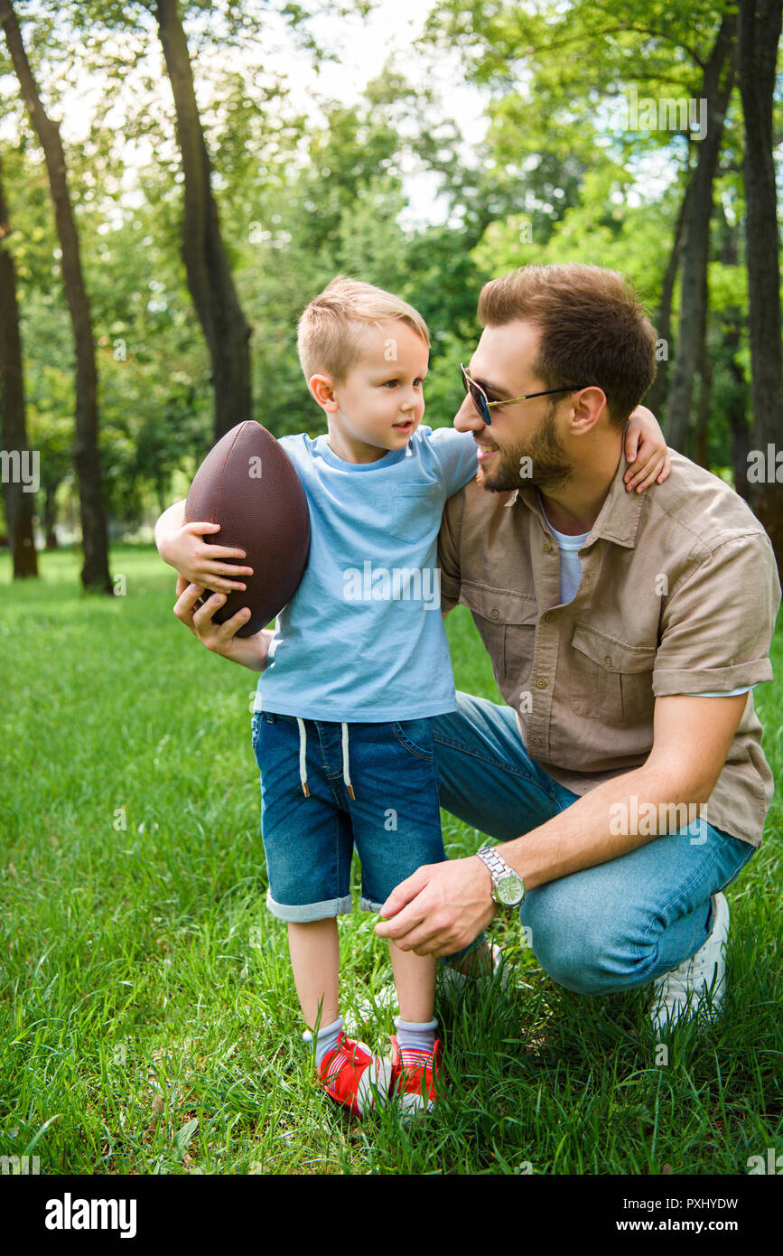 father and son hugging and holding american football ball at park Stock ...