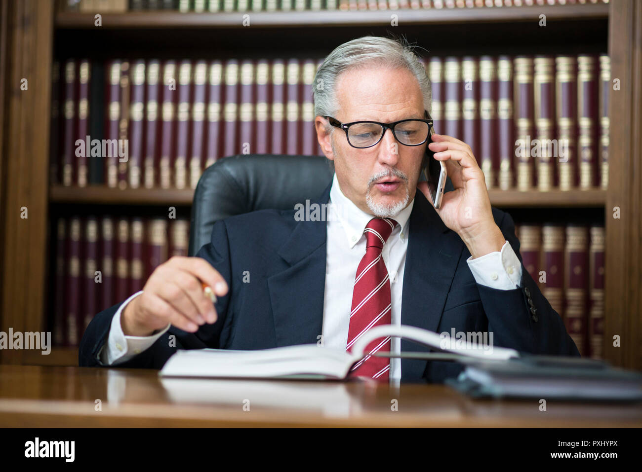 Businessman reading a book while talking on his mobile phone Stock ...