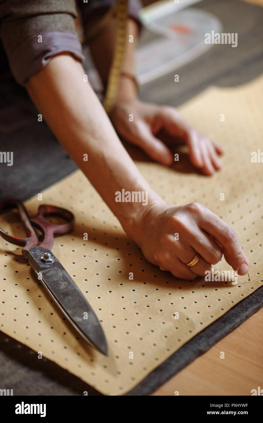 Tailor sticking a pin to cloth pattern at sewing workshop female Stock ...
